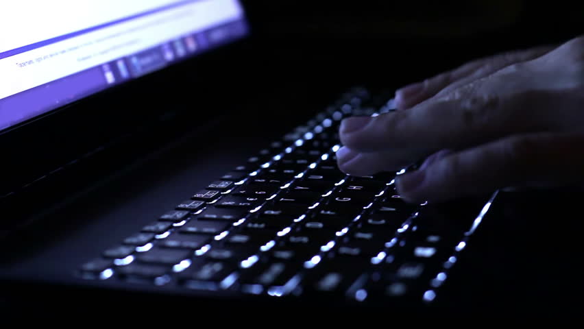 Hacker Typing On Keyboard With A Program In The Background Stock