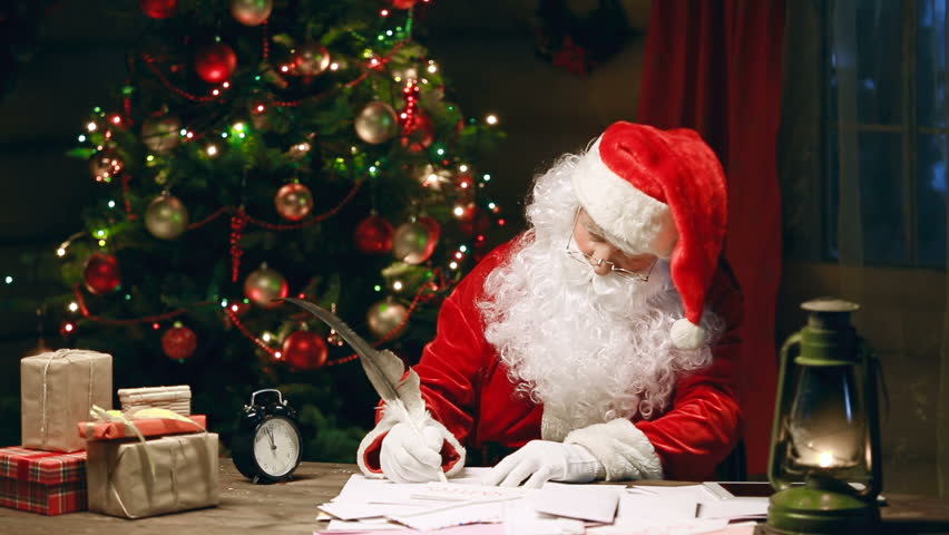 Santa Claus Sitting At The Table And Reading Wish Letters From Kids ...